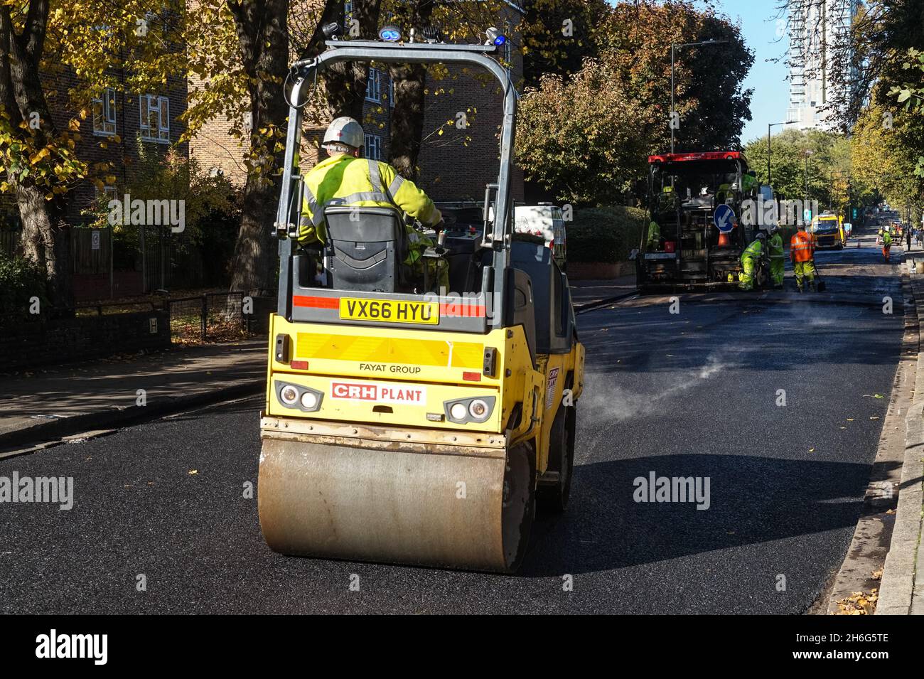 Workers using road roller in street resurfacing works in London England ...