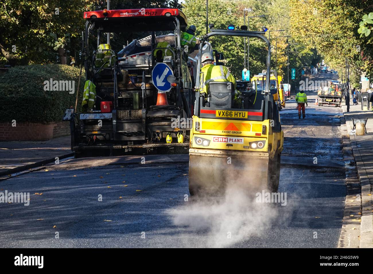 Workers using road roller in street resurfacing works in London England ...
