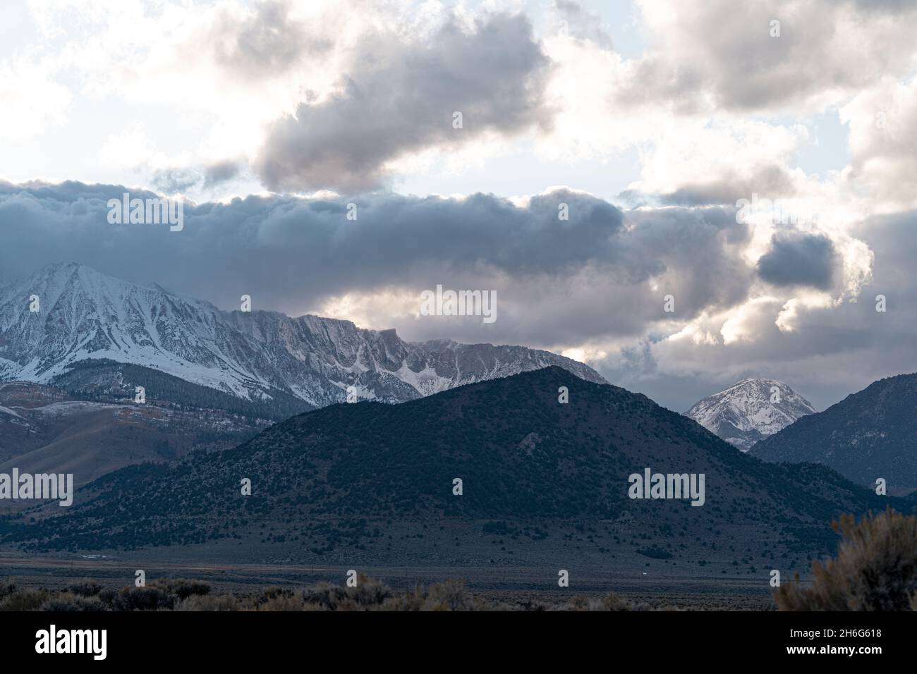 Mesmerizing view of a cloudscape over the snowy mountains and hills with little vegetation Stock ...