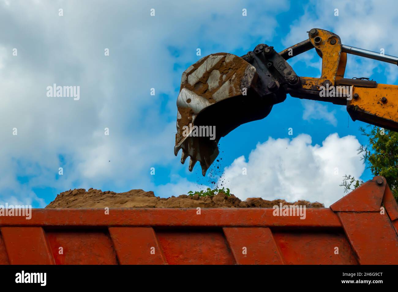 Orange excavator loading soil into a dumper truck on construction site ...