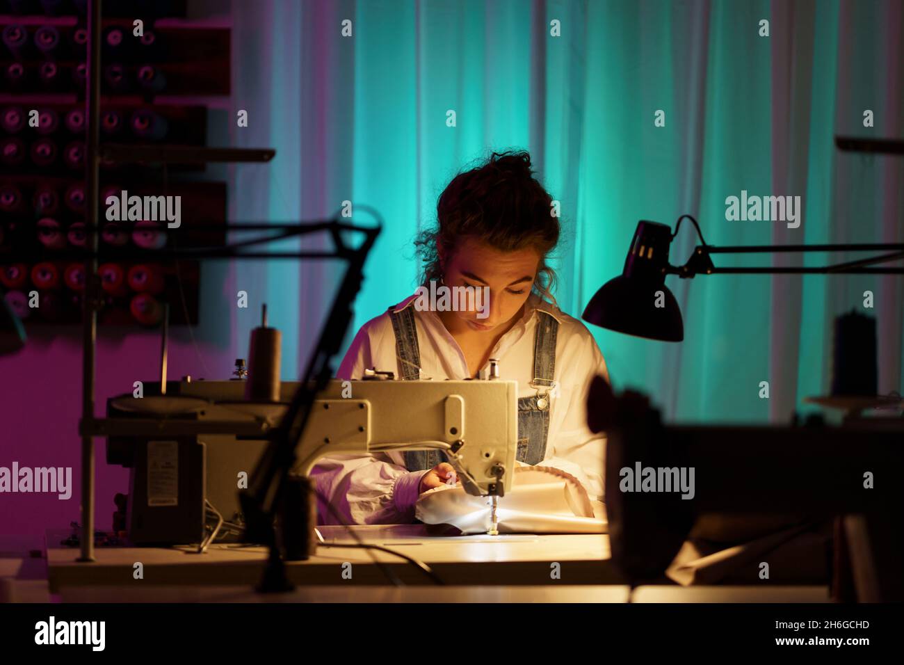 Self-employed young woman work on sewing machine in little creative ...