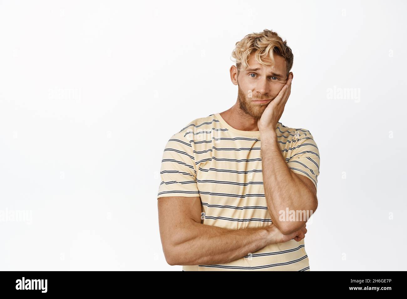 Portrait of handsome blond man looking sad or bored, leaning face on ...