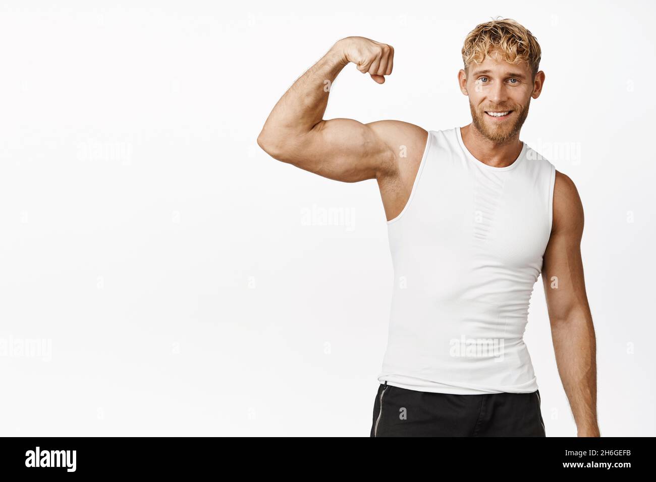 Smiling sportsman flex biceps, showing strong arm mucles and looking ...