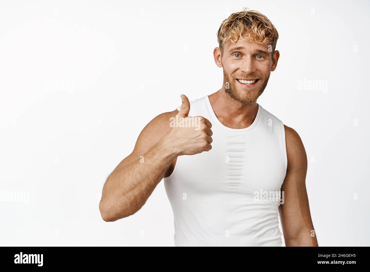 Smiling sportsman showing thumbs up in approval, fitness athlete gives ...