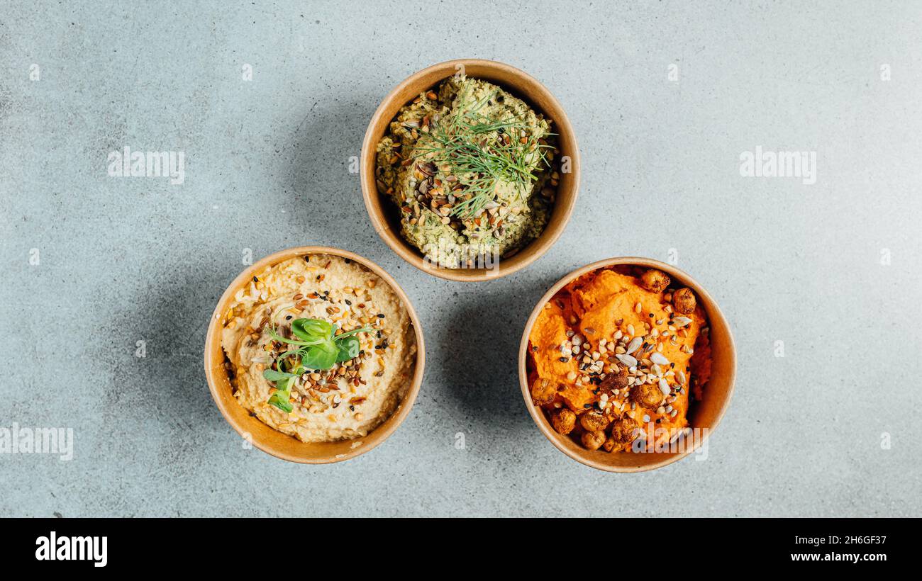 Top shot of three different hummuses in wooden bowls Stock Photo - Alamy