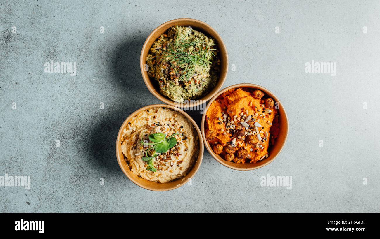 Top shot of three different hummuses in wooden bowls Stock Photo - Alamy