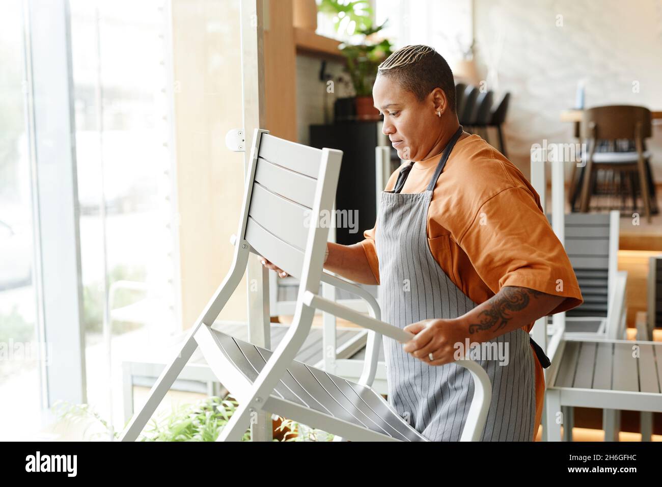 Side view shot of stylish young woman working in modern cafe placing ...