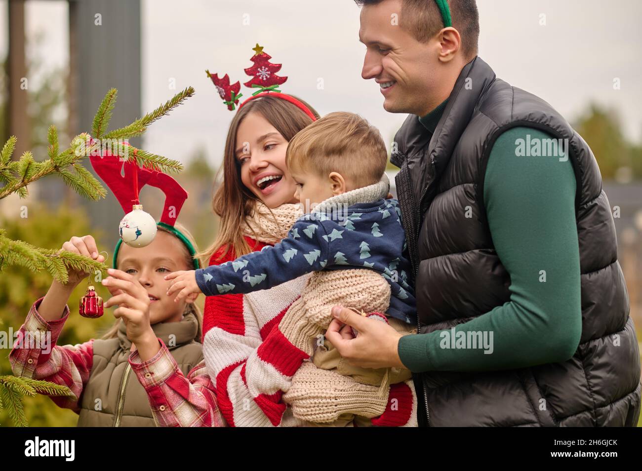 Smiling people decorating a christmas tree Stock Photo - Alamy