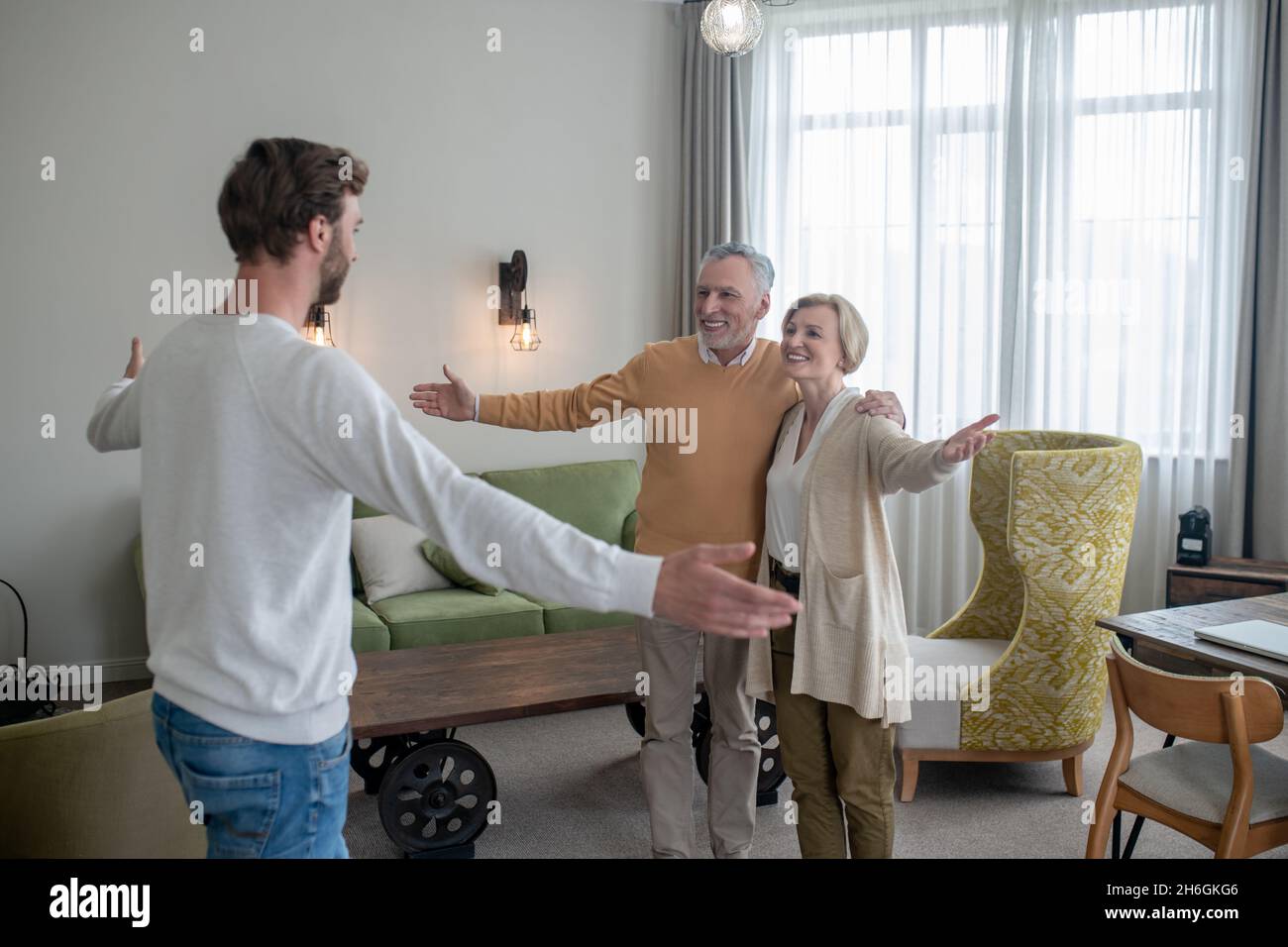 Young man visiting his parents and family looking happy Stock Photo - Alamy