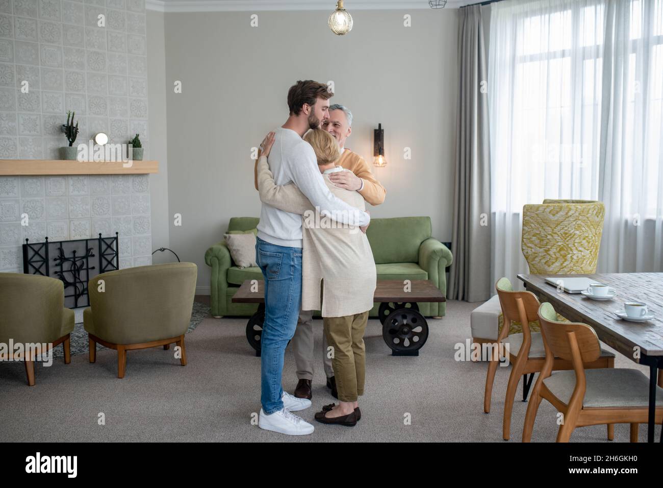 Young man visiting his parents and family looking happy Stock Photo - Alamy
