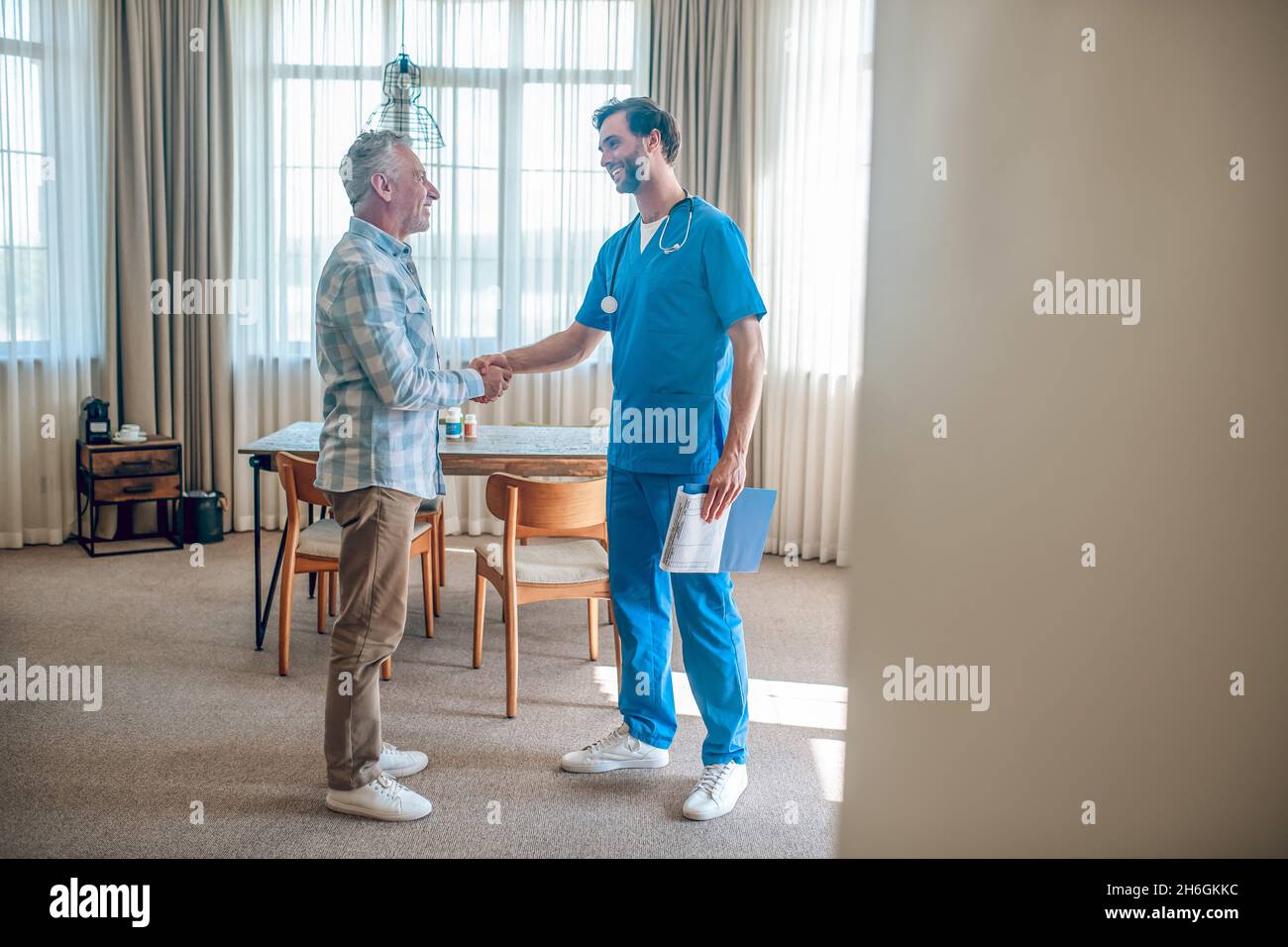Pleased patient greeting his doctor in his house Stock Photo - Alamy