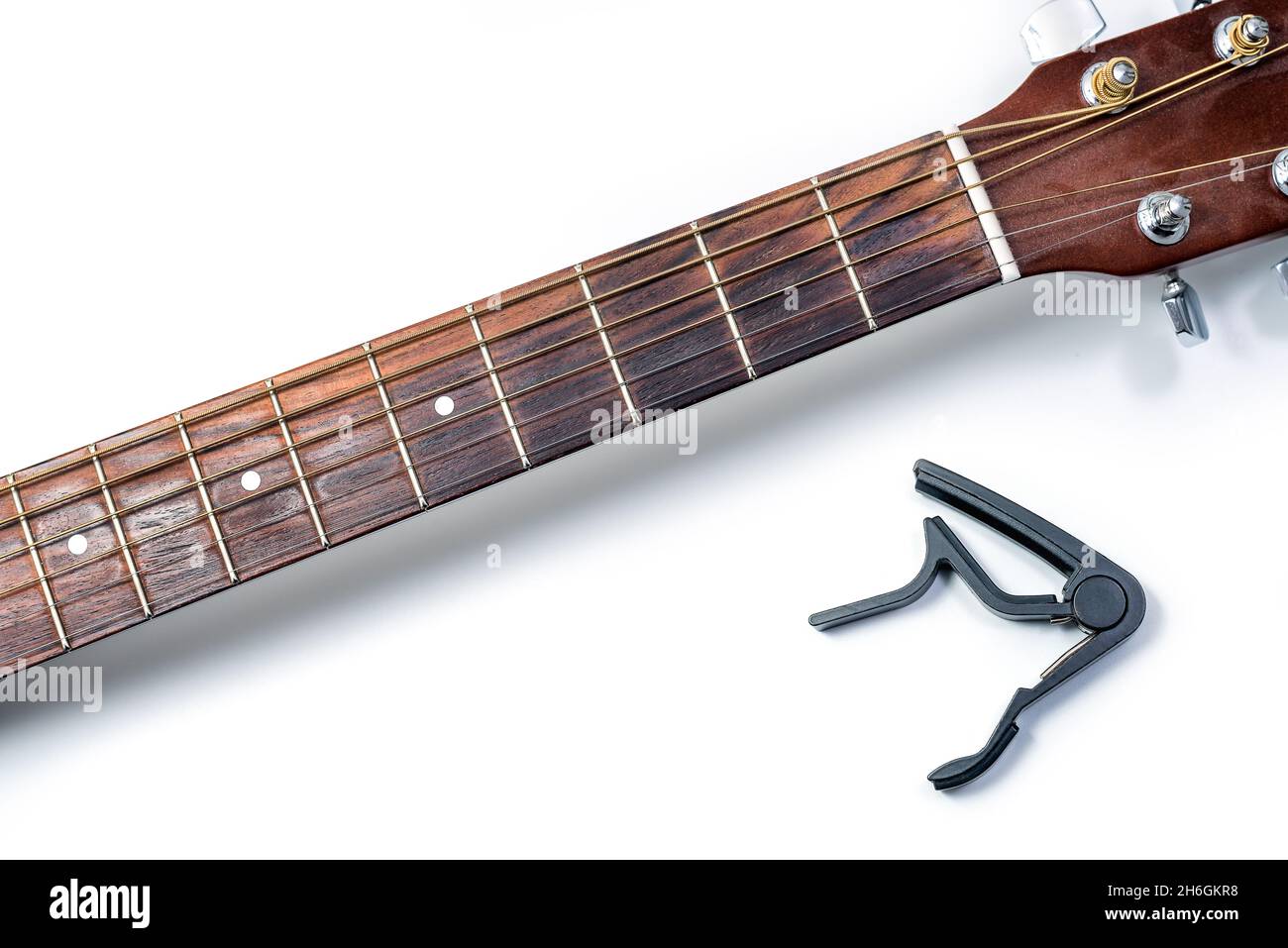 Classic acoustic guitar and a capo on a white background, close-up ...