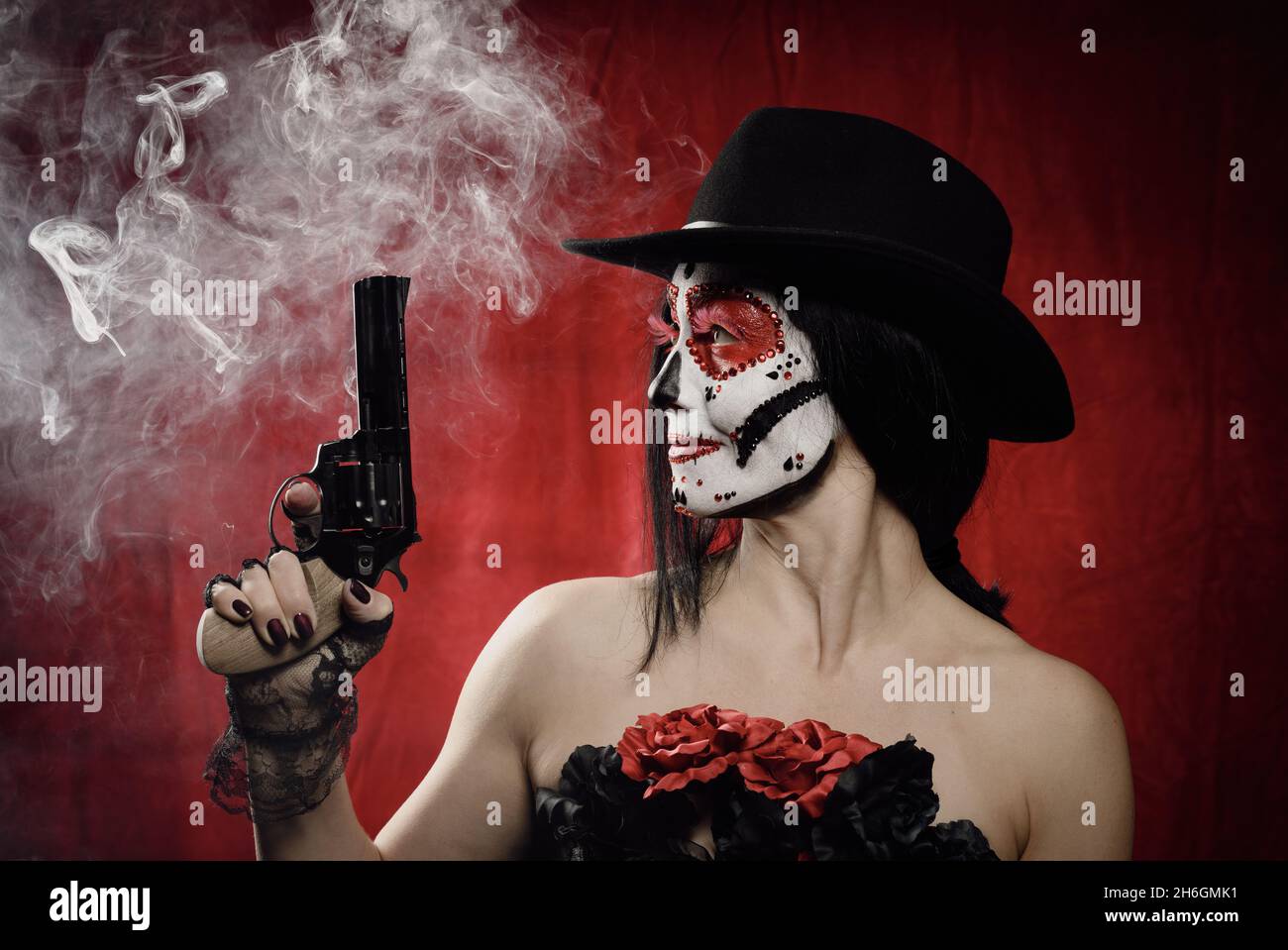beautiful woman in skeleton make-up holds a revolver, she is wearing a ...