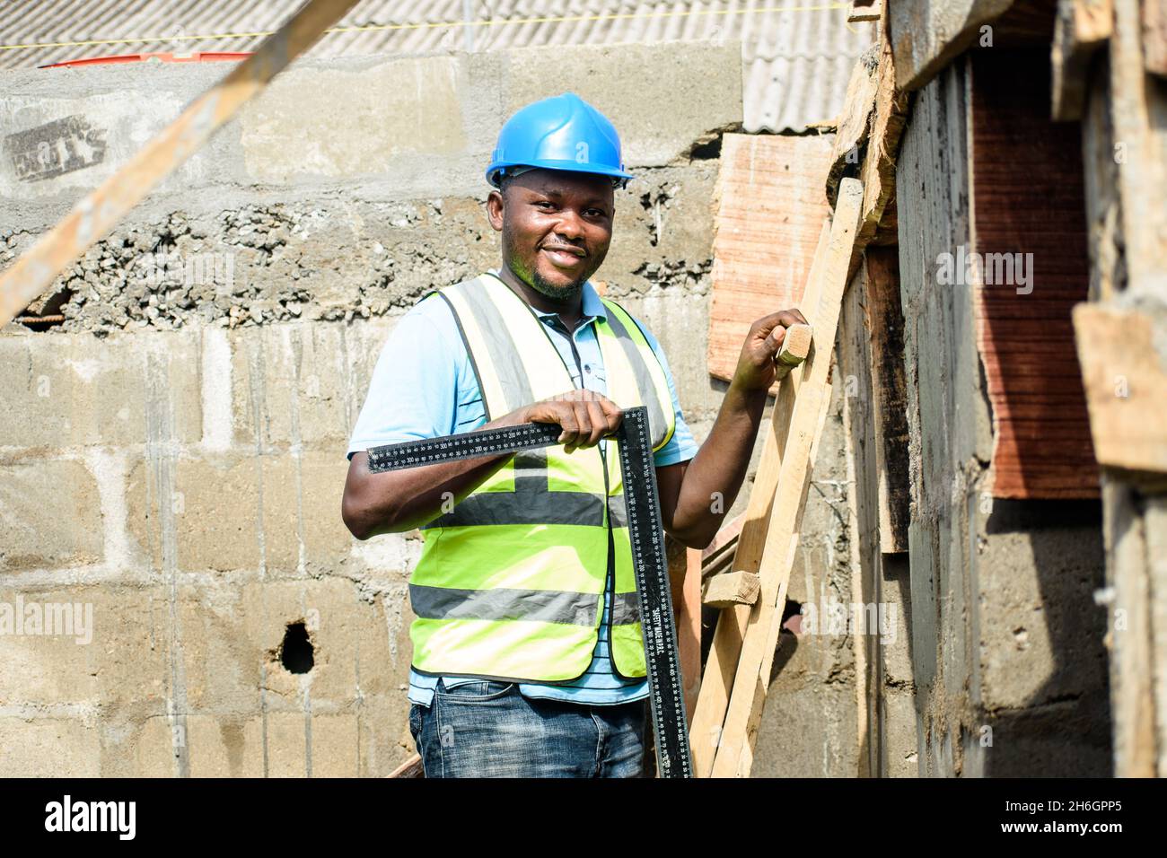 African male construction working with L shape ruler on a building site ...