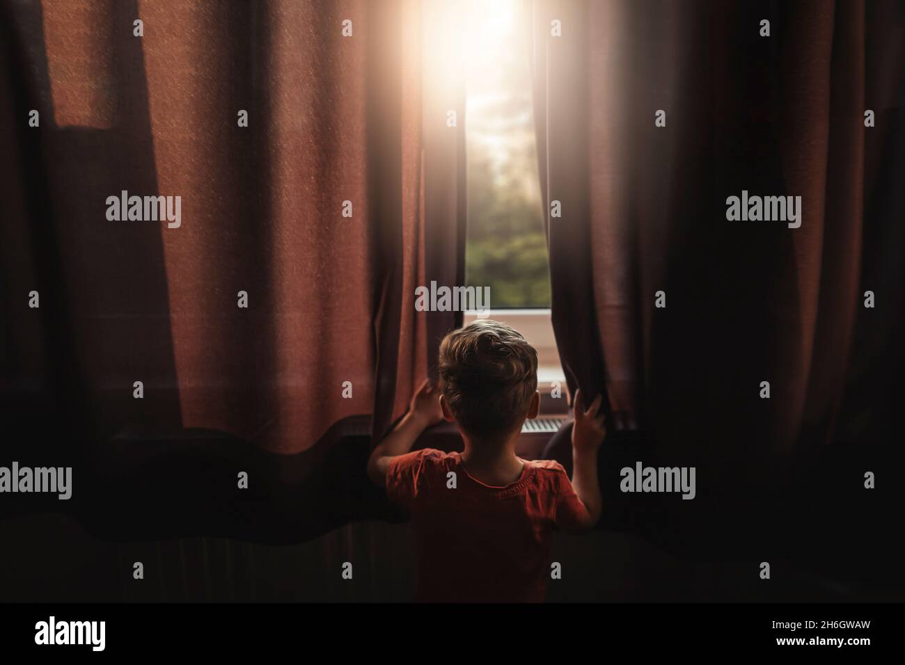 Back view of boy peaking outside through windows Stock Photo - Alamy