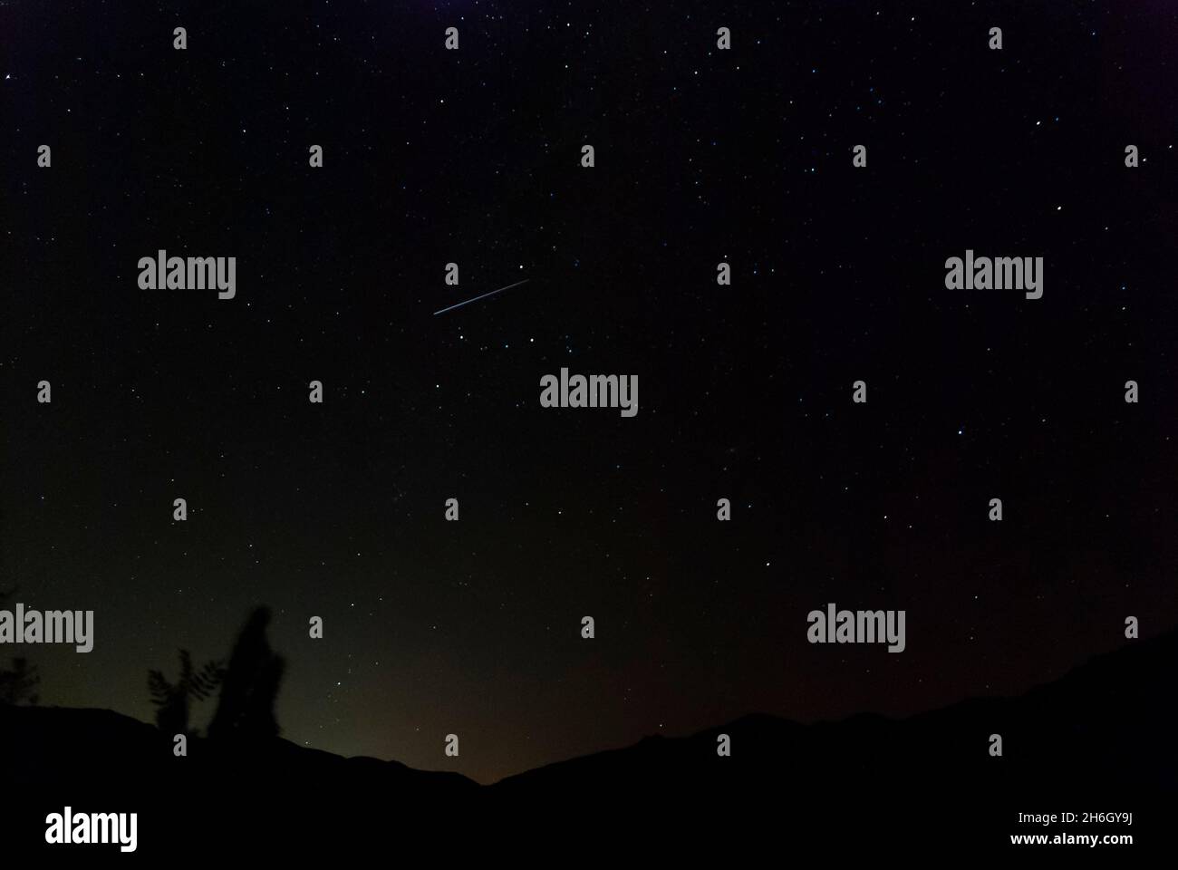 Night scene with starry sky with Perseid meteor shower running through ...