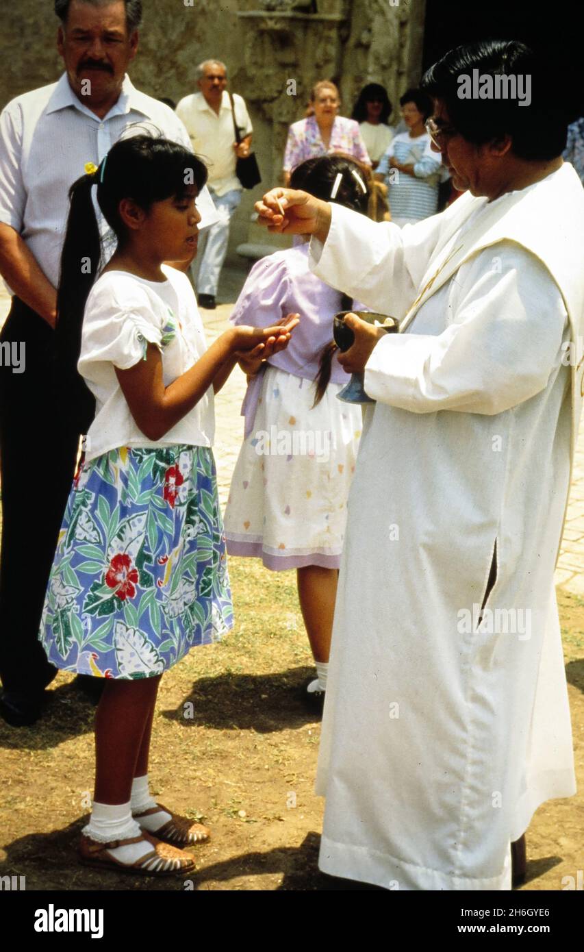 San Antonio Texas USA, circa 1988: Catholic priest gives communion to ...