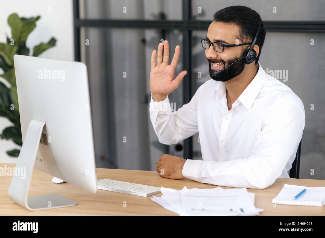Successful positive Indian handsome business man, ceo, sits at a desk in the office ...