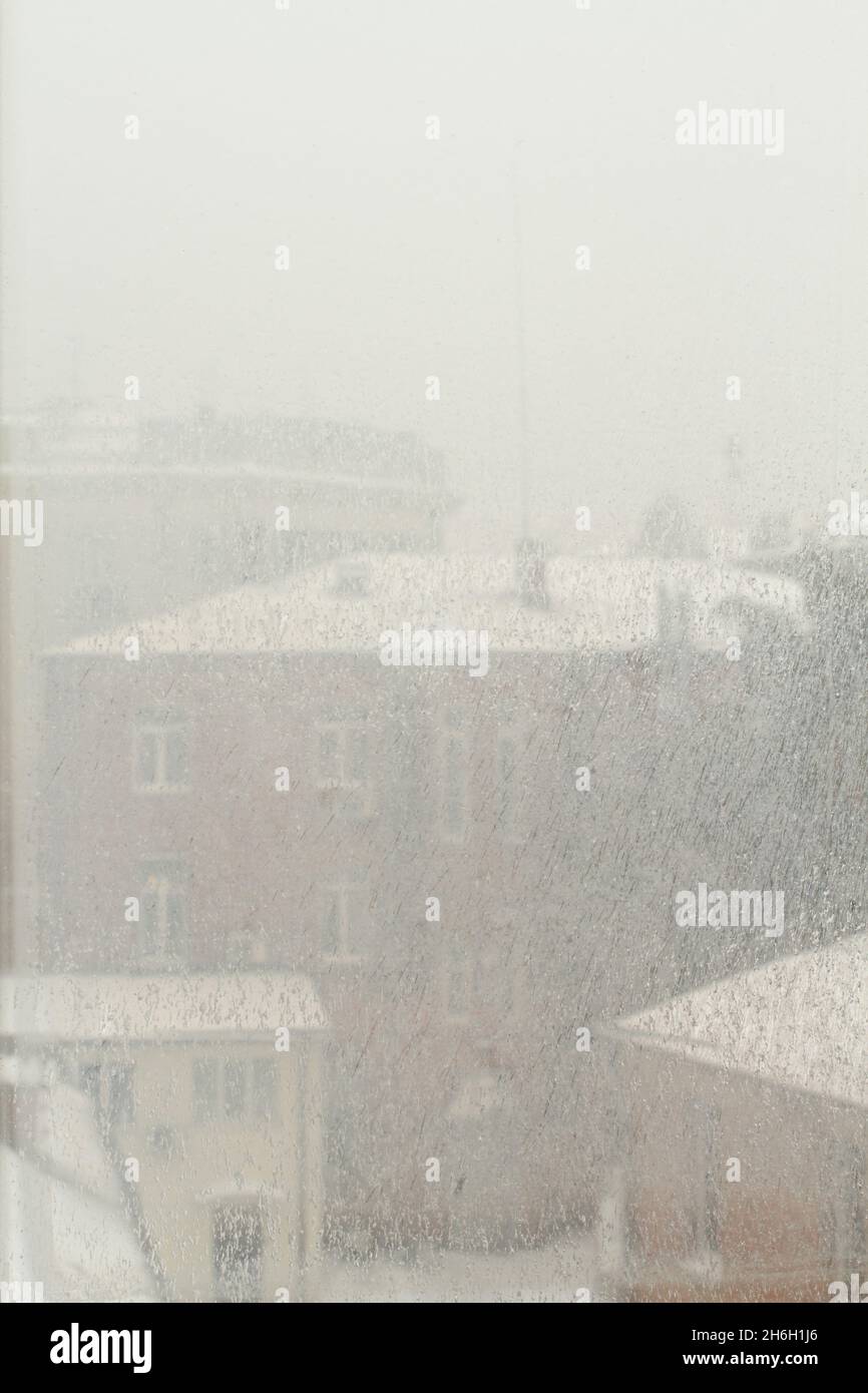 Street view through an ice-covered window outside. Dull cloudy winter ...
