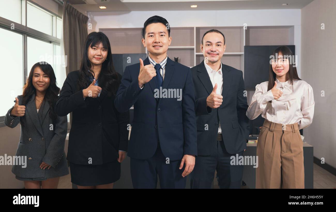 Business team showing thumbs up sign gesture and looking at camera ...