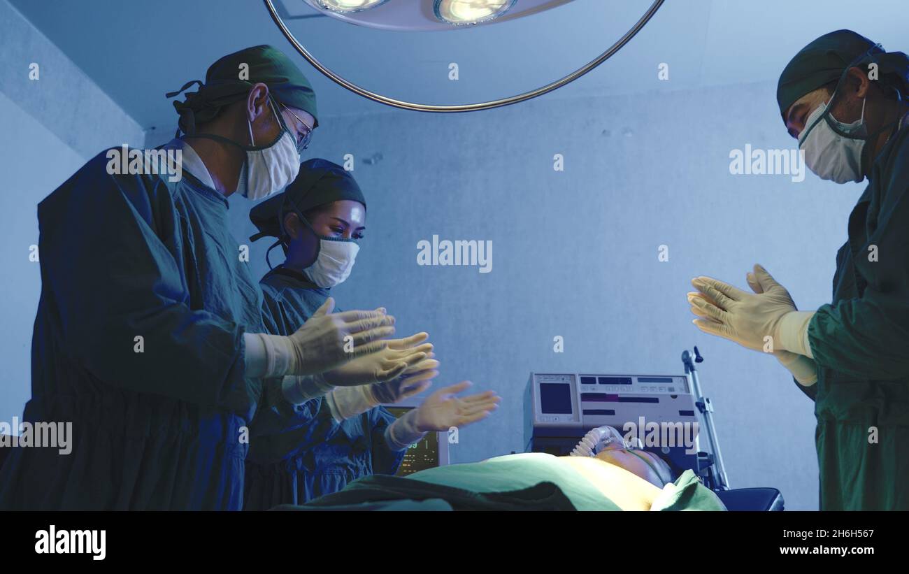 Group of surgery doctors in sterile gloves and protective face masks ...