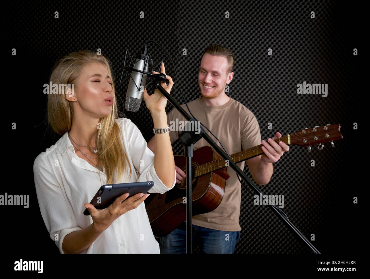 Young female singing with tablet computer in her hand. While the man ...