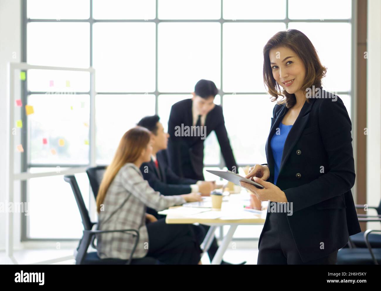 An Asian businesswoman in suit standing with tablet computer in her ...