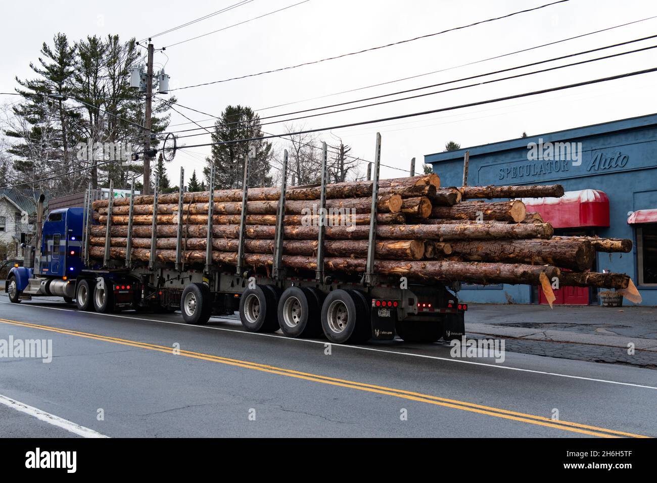 A large tractor trailer hauling long logs to be made into utility or ...