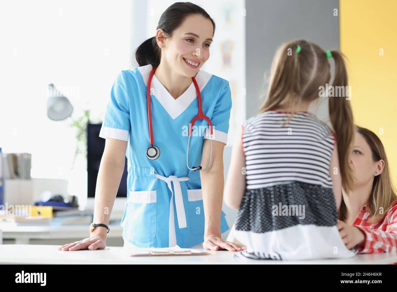 Smiling professional pediatrician talk to young cute patient girl on ...