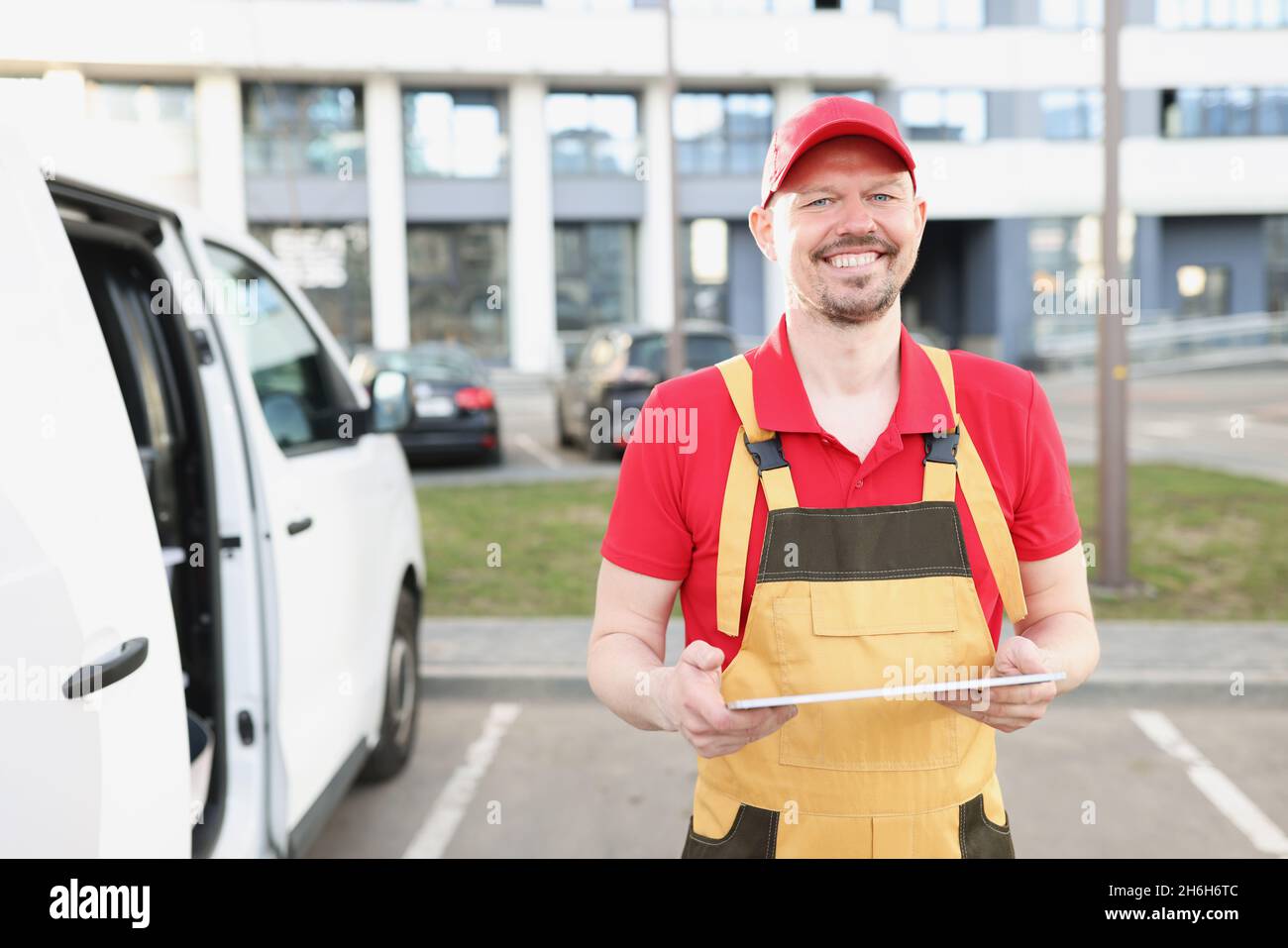 Smiling delivery man stand on street with delivery receipt paper and ...