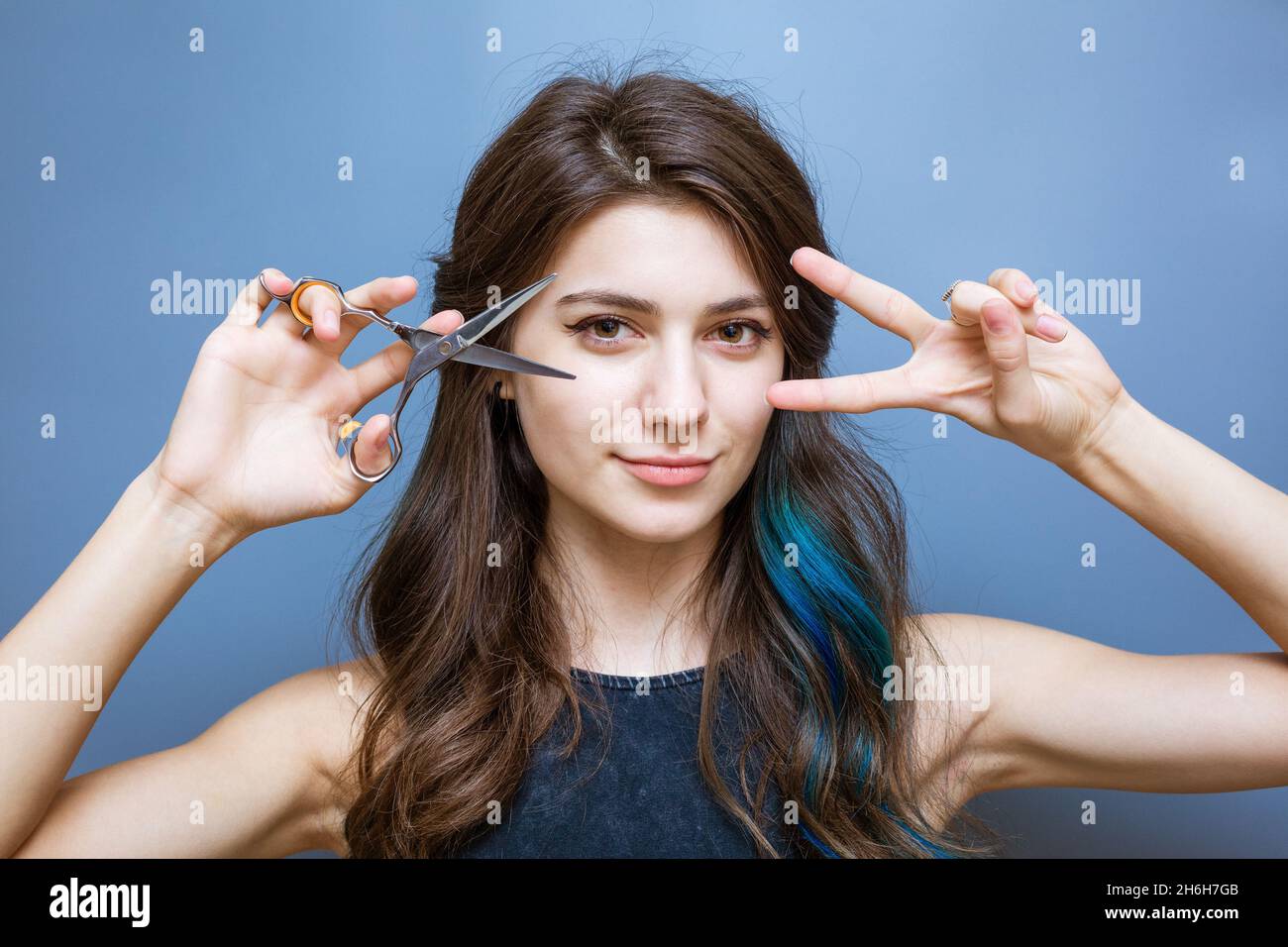 Cute young woman with brunette with blue strands of hair holding ...