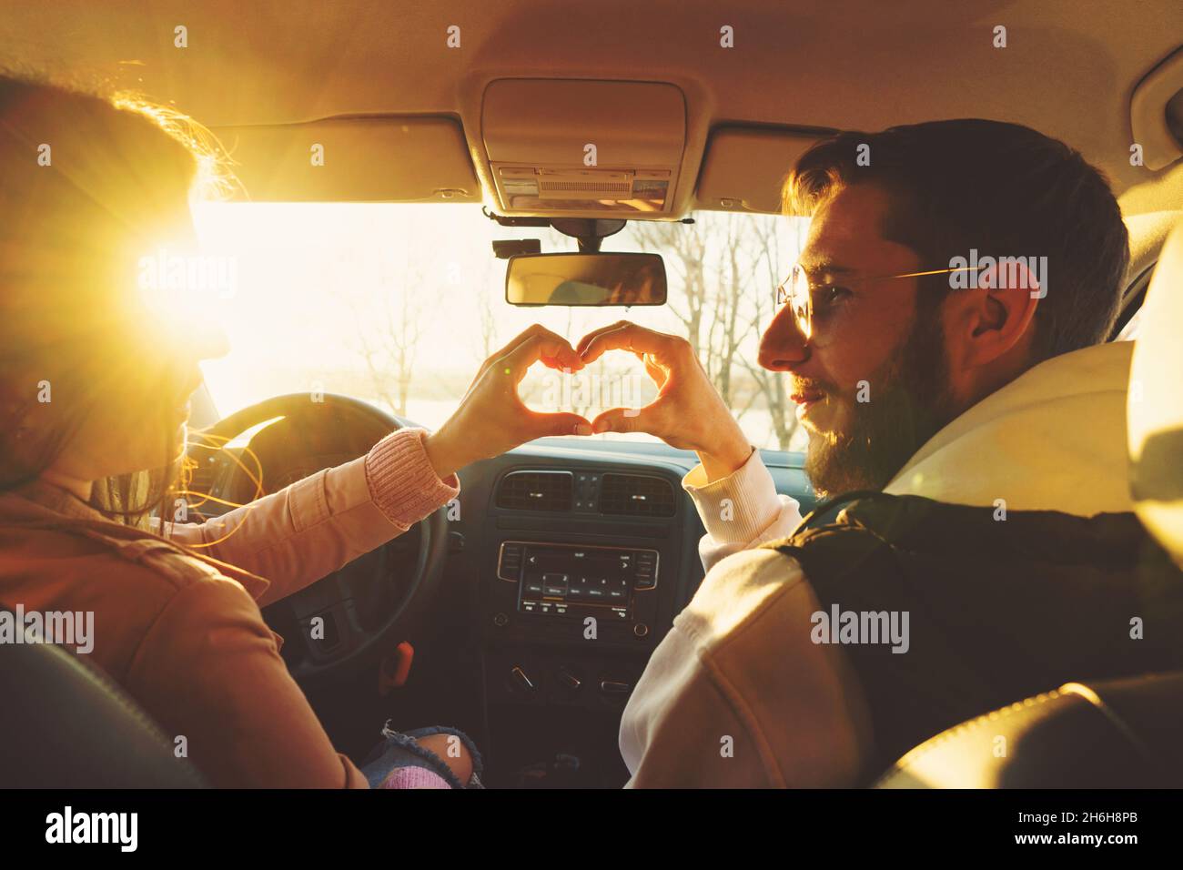 Romantic couple makes heart shape with their hands in car. Female and ...