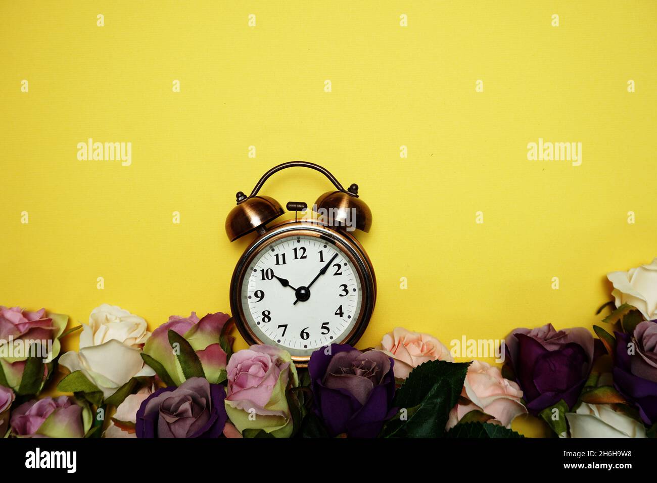 Alarm clock with Rose flower bouquet on yellow background Stock Photo ...