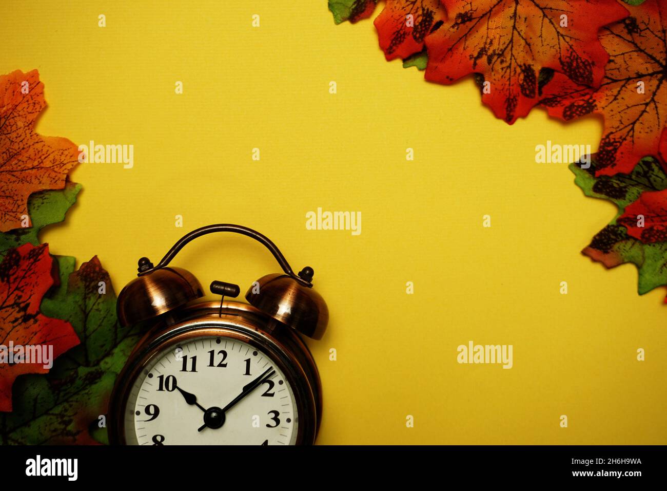 Alarm clock with Maple leaf boder on Yellow background Stock Photo - Alamy