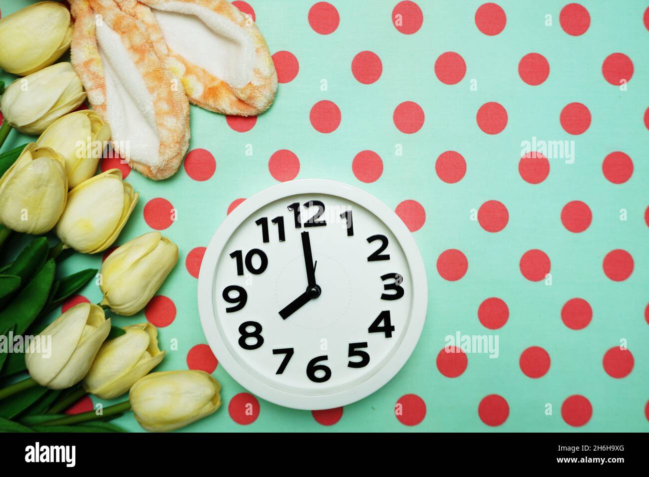Rabbit ears and Alarm clock with tulip flower bouquet on green polka ...