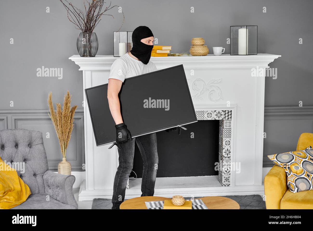 Thief with black balaclava stealing modern expensive television. Masked ...