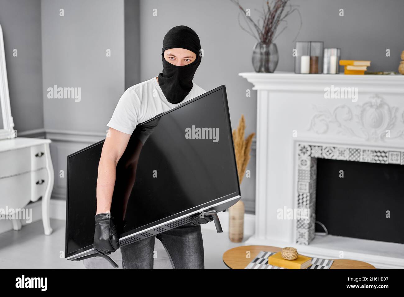 Thief with black balaclava stealing modern expensive television. Masked ...