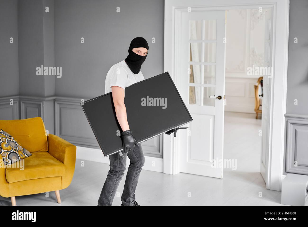 Thief with black balaclava stealing modern expensive television. Masked ...