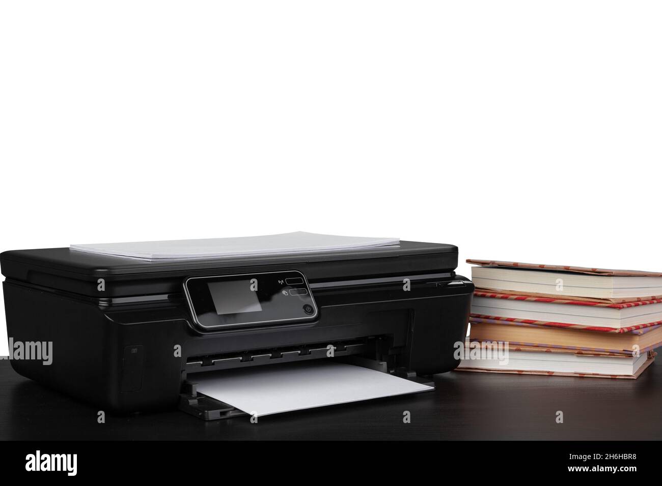 Printer and stack of books on black table against white background ...
