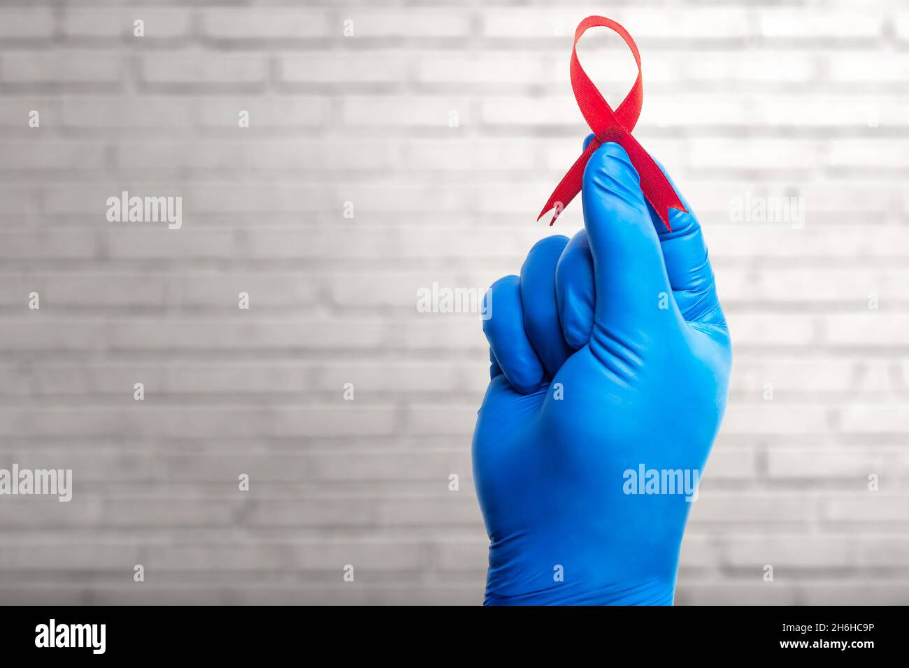 Red ribbon and medical glove with brick wall background. Hiv Aids ...