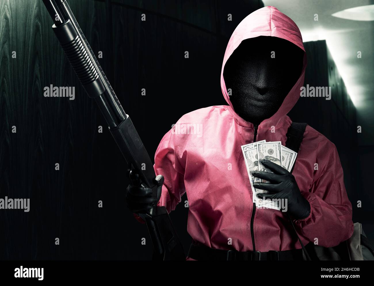Criminal man in pink uniform and a hidden mask holding the shotgun and ...