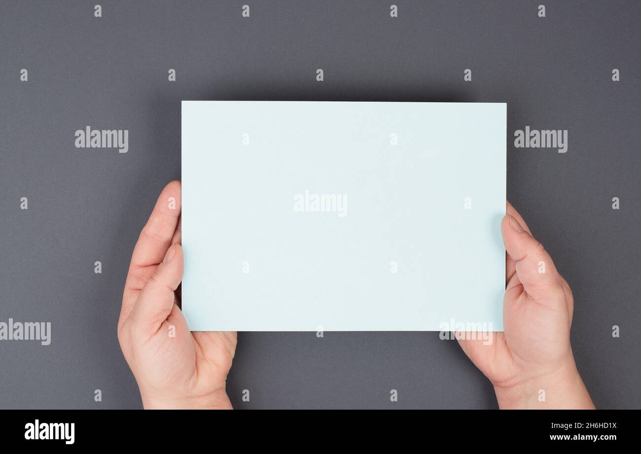Holding empty paper in the hands, grey colored background, copy space ...