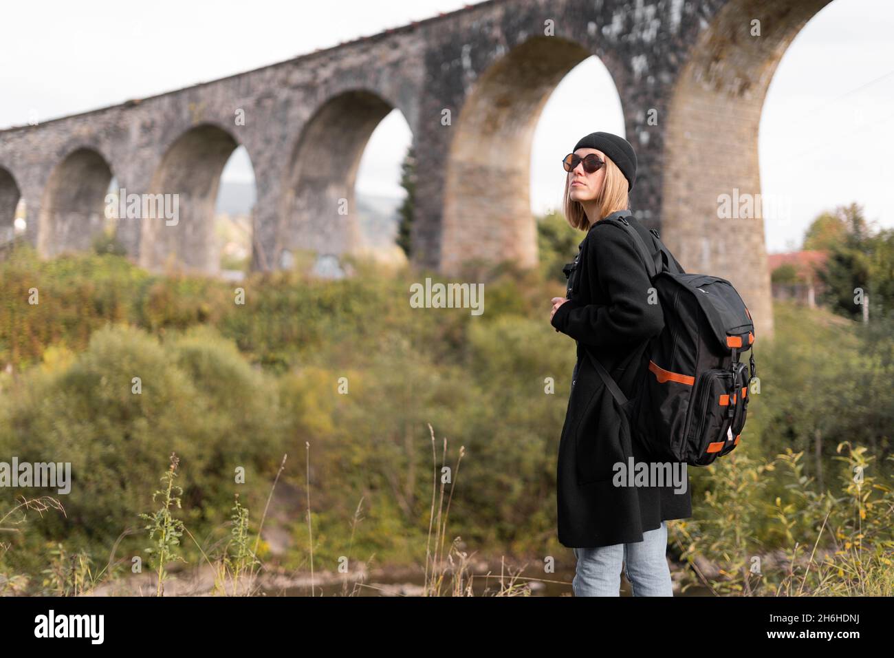 Girl traveler near the old arch bridge traveling through Europe, stone ...