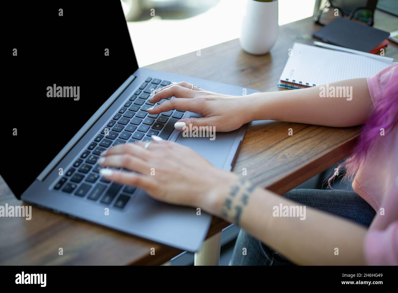 Back view of a young pink hair woman keyboarding on laptop computer ...