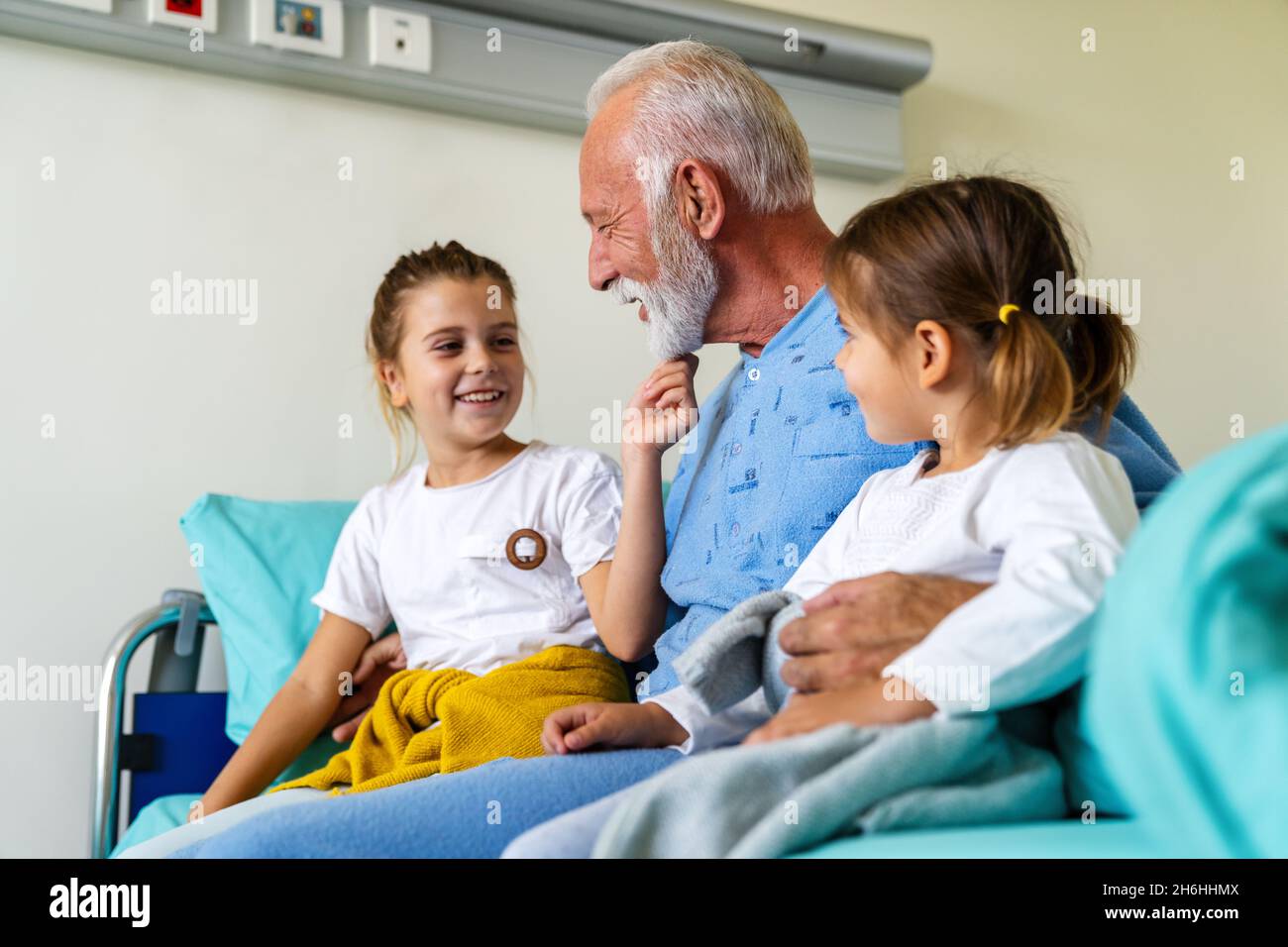 Happy grandchildren visiting grandfather at hospital ward. Support ...