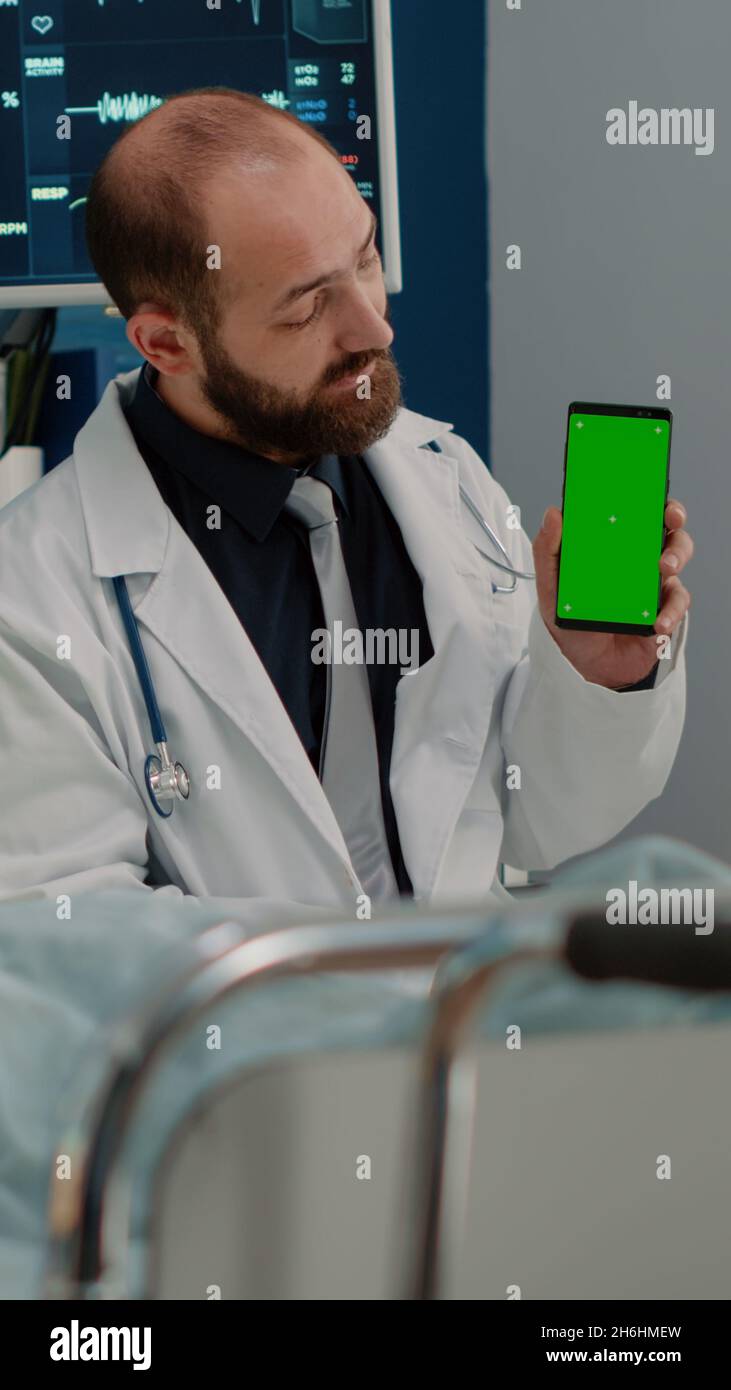 Doctor and sick patient looking at green screen on phone at nursing ...