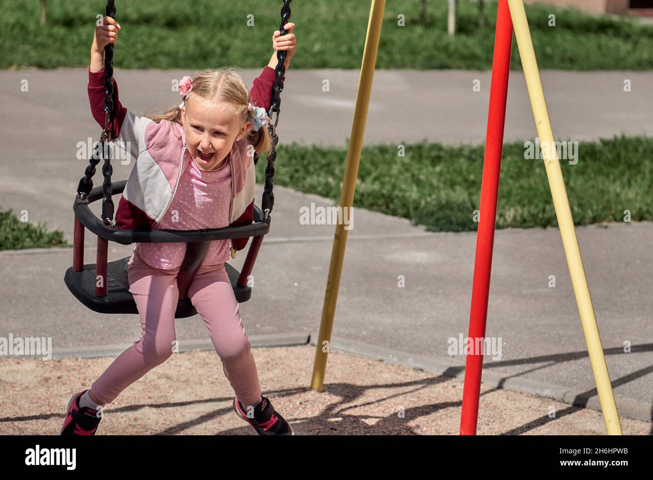 Kids play on the playground. Happy laughing girl have fun swinging and ...