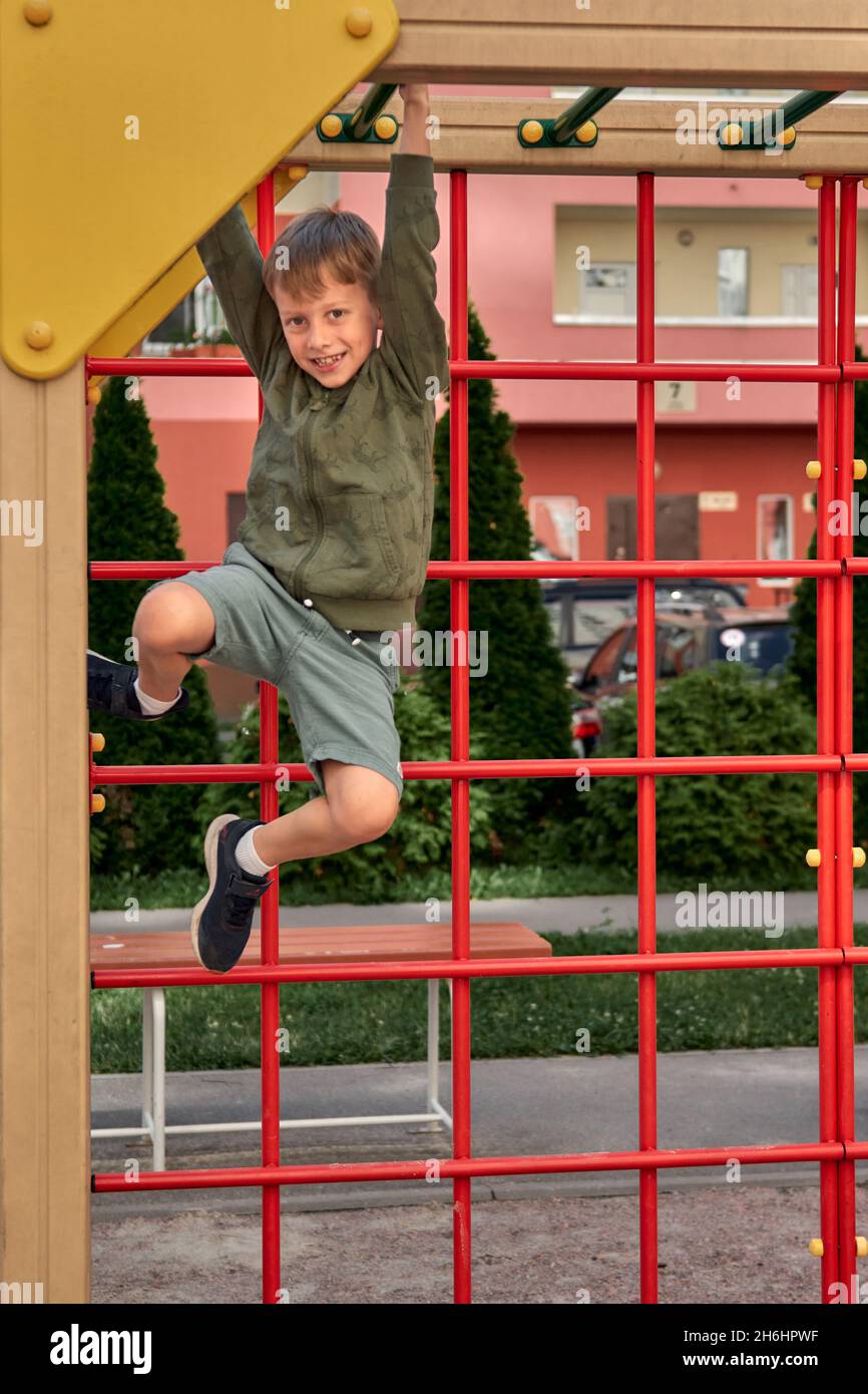 Kids play on the playground. Happy laughing boy have fun swinging and ...