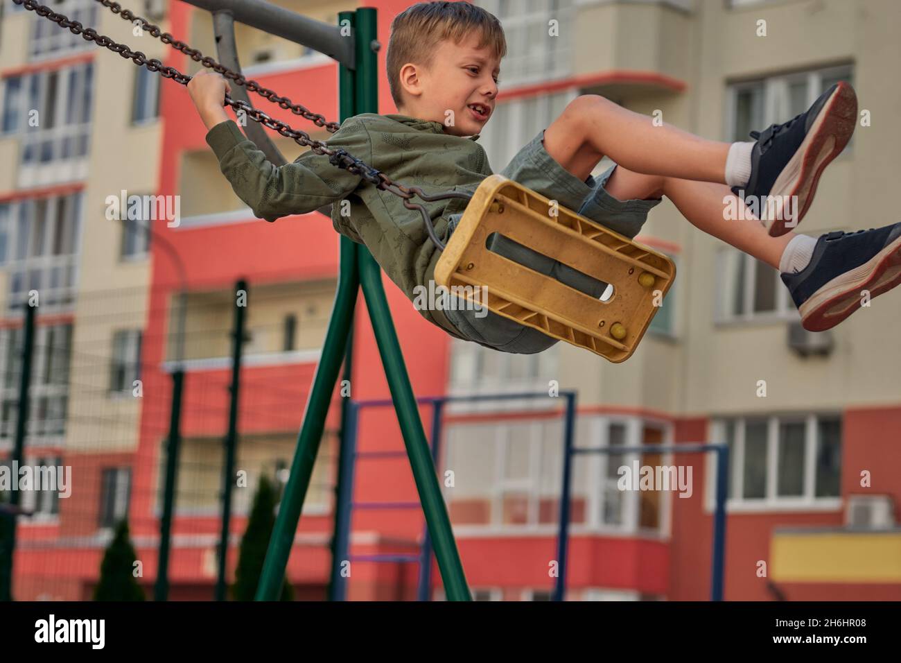 Kids play on the playground. Happy laughing boy have fun swinging and ...