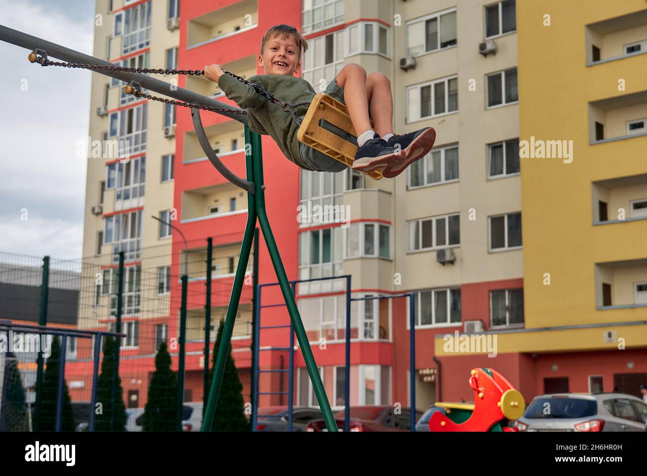 Kids play on the playground. Happy laughing boy have fun swinging and ...